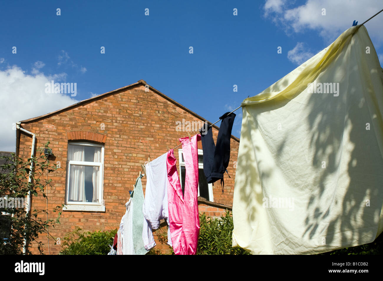 Clothes hanging on a clothes line with a house and a blue sky ...