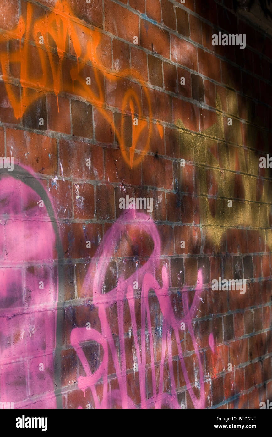 Sun reflecting off water on a shady brick bridge wall with graffiti ...