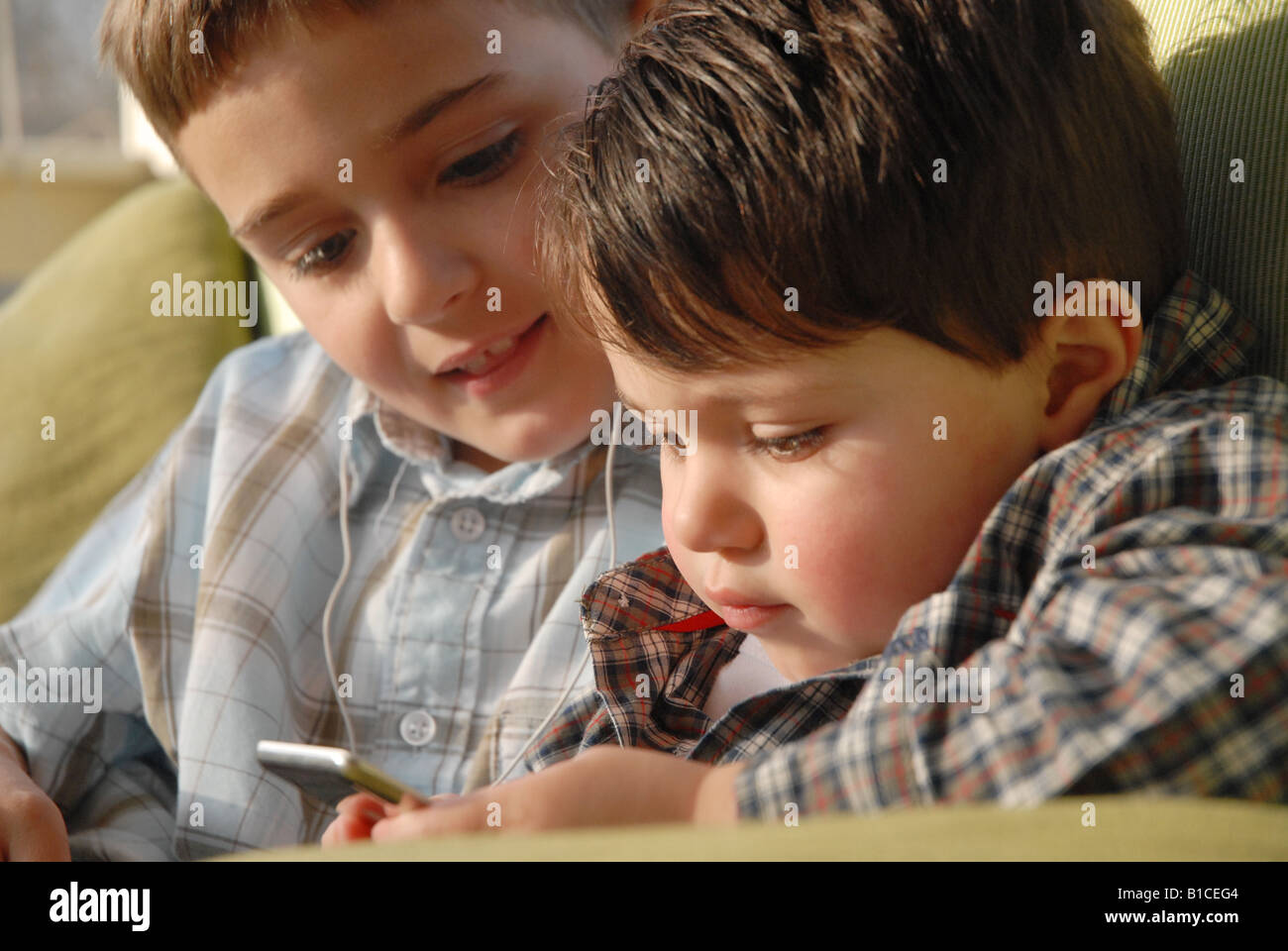 Ten year old boy shows his two year old cousin how to operate a new ...