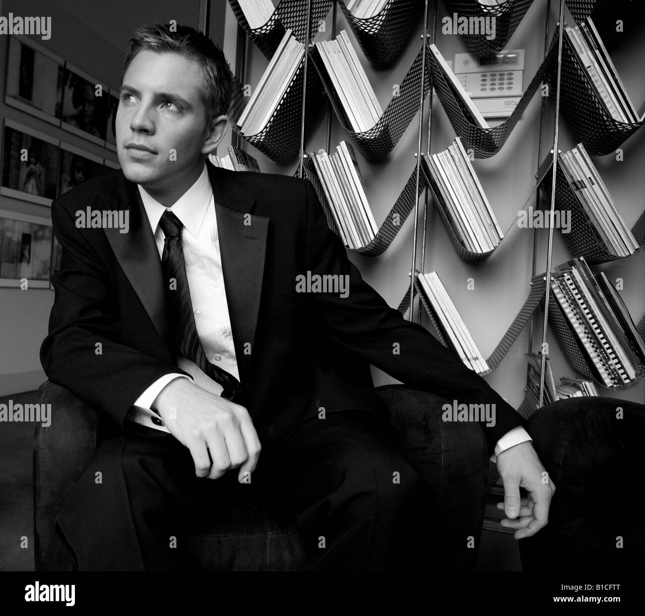 man in suit waits in front of magazine display rack Stock Photo - Alamy