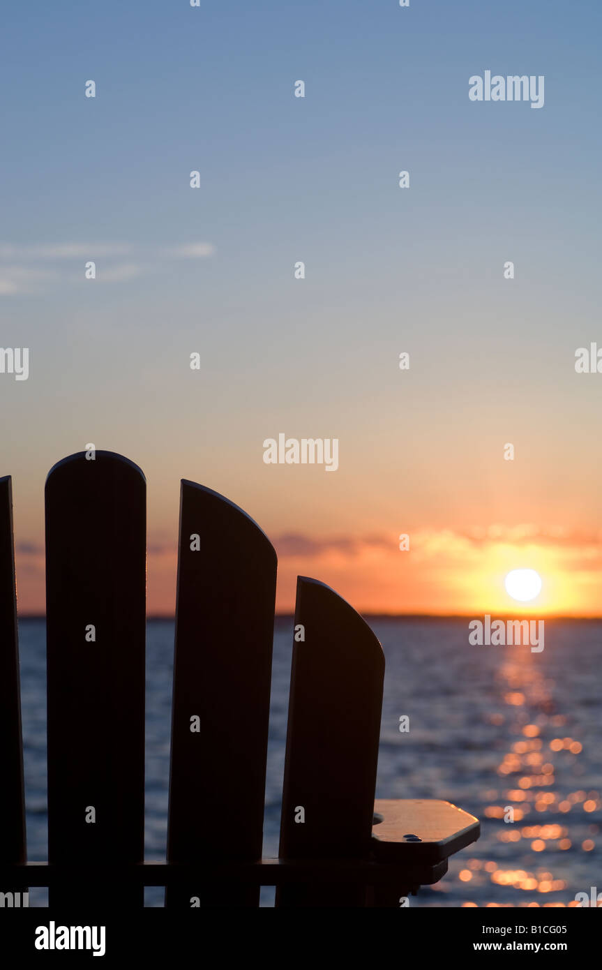 THE SUNSETS OVER A LAKE WITH ADIRONDACK CHAIR Stock Photo - Alamy