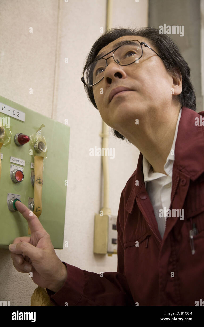Senior worker pressing button Stock Photo - Alamy