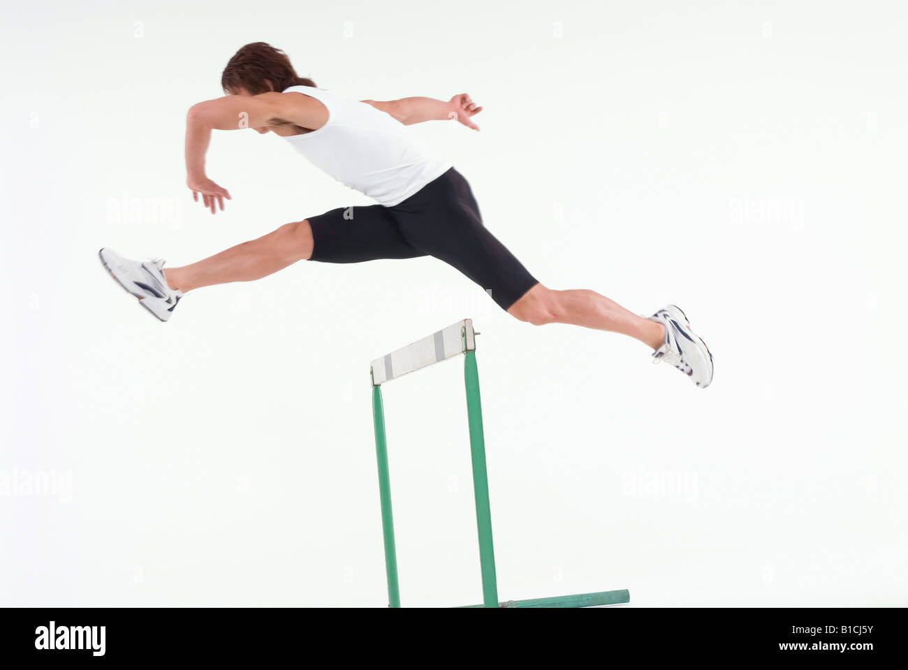 Young man jumping hurdle Stock Photo - Alamy
