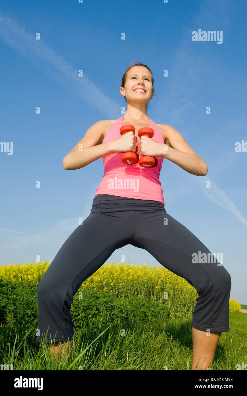 young woman lifting barbells outdoor, knee bend Stock Photo - Alamy
