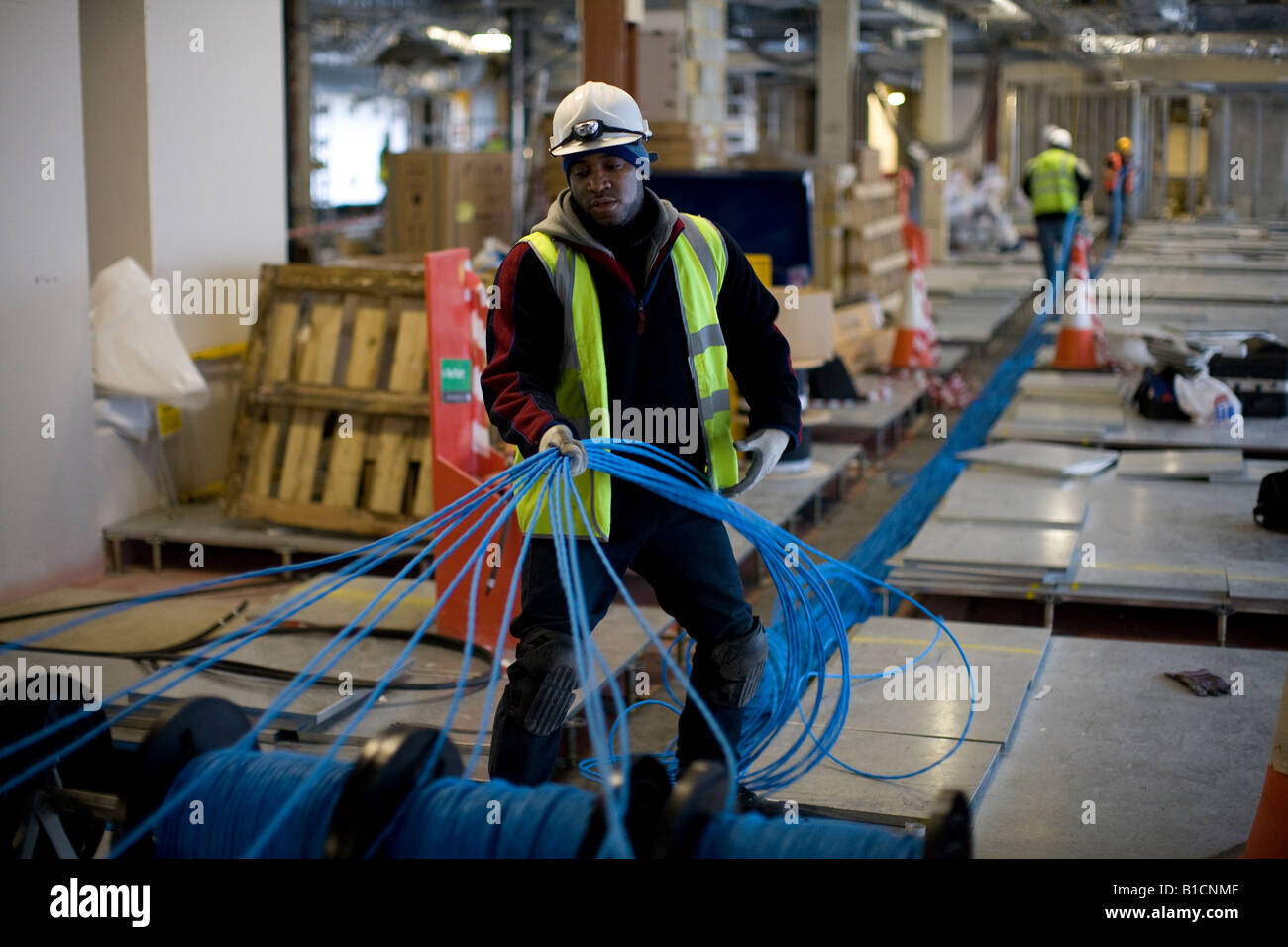 Electricians gather data cables from drums and lay them out form ...