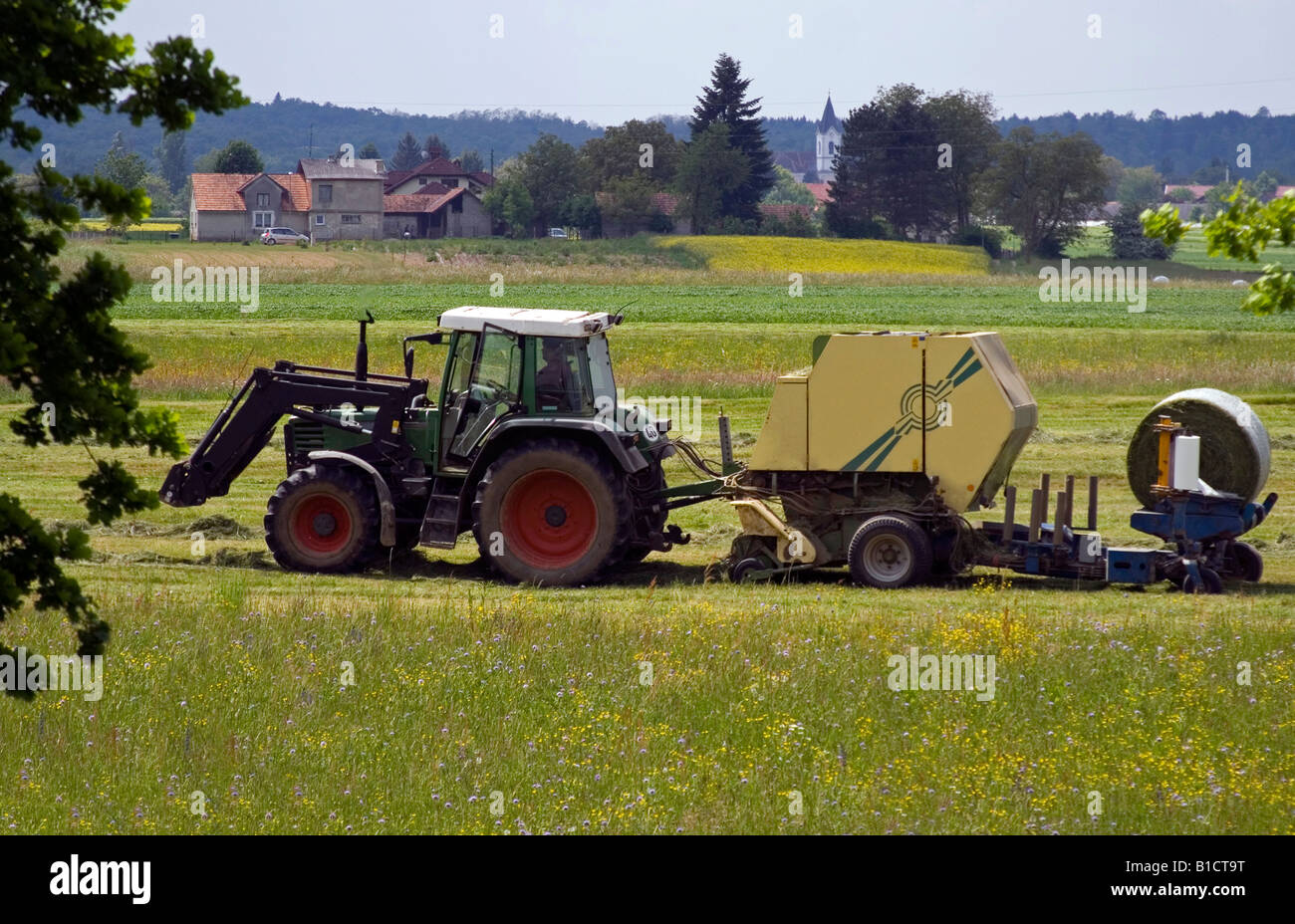 Tractor collecting and packing hay with machine Stock Photo - Alamy