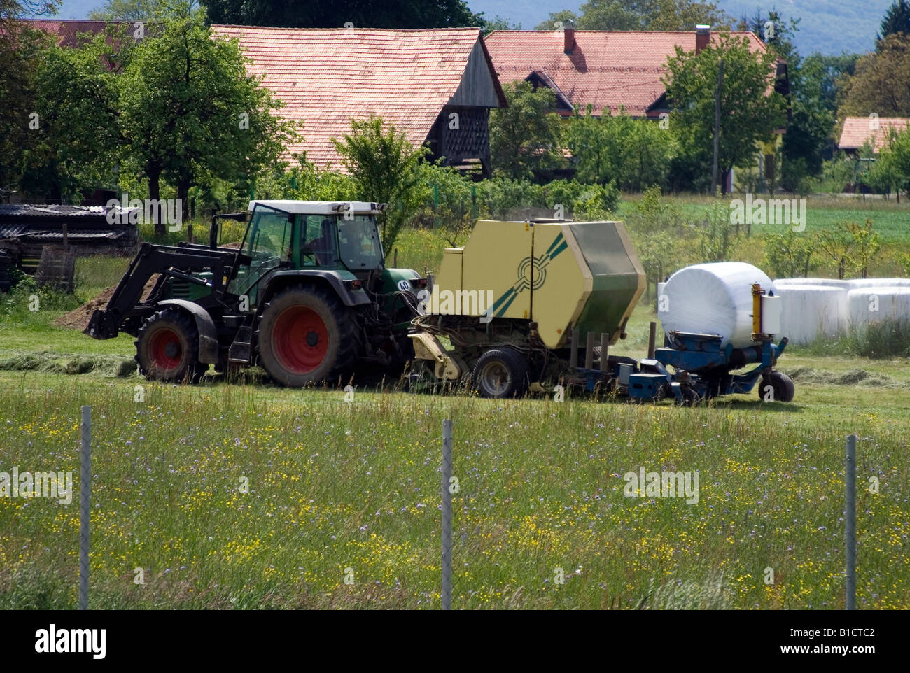 Tractor collecting and packing hay with machine Stock Photo - Alamy