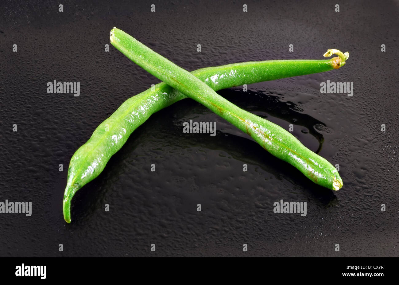 Two fresh green beans on a watery black plate Stock Photo - Alamy