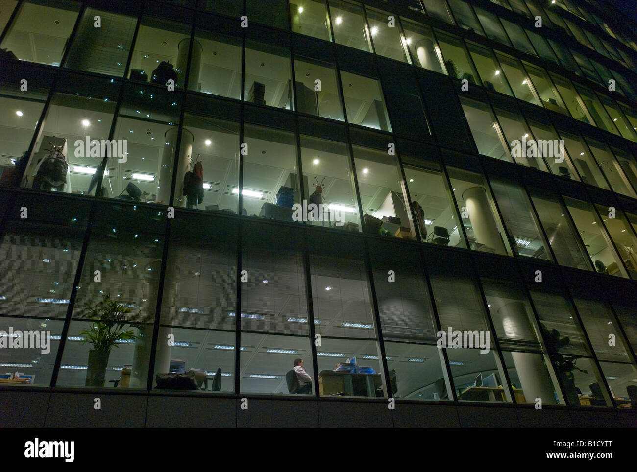 Offices with windows lit at night. One man still visible working at his ...