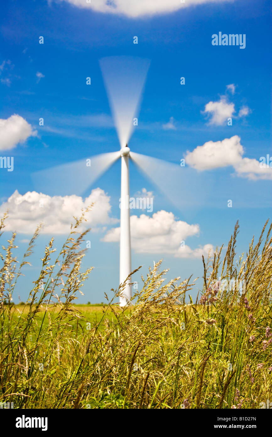 Single wind turbine with blades turning against a deep blue summer sky ...