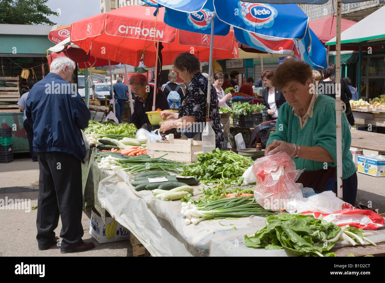 Outdoor street market stall woman stallholder selling fresh vegetables ...