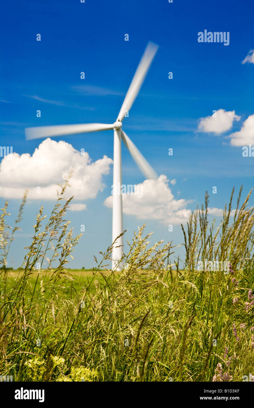 Single wind turbine with blades turning against a deep blue summer sky ...