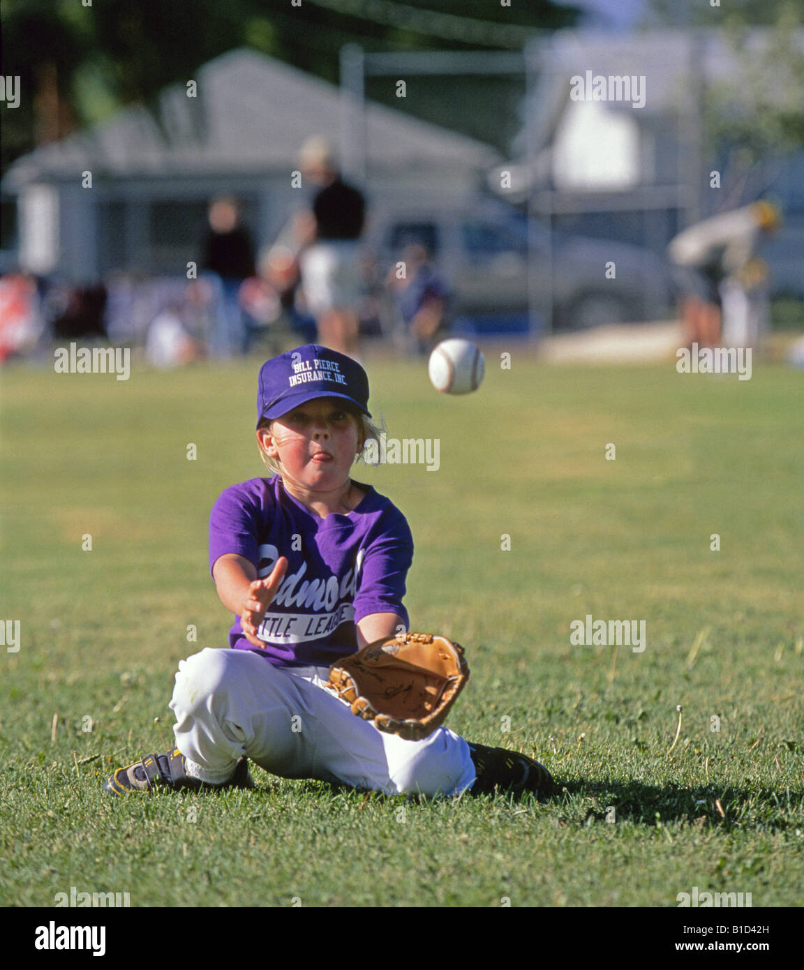A young girl playing little league softball catches a softball in a ...