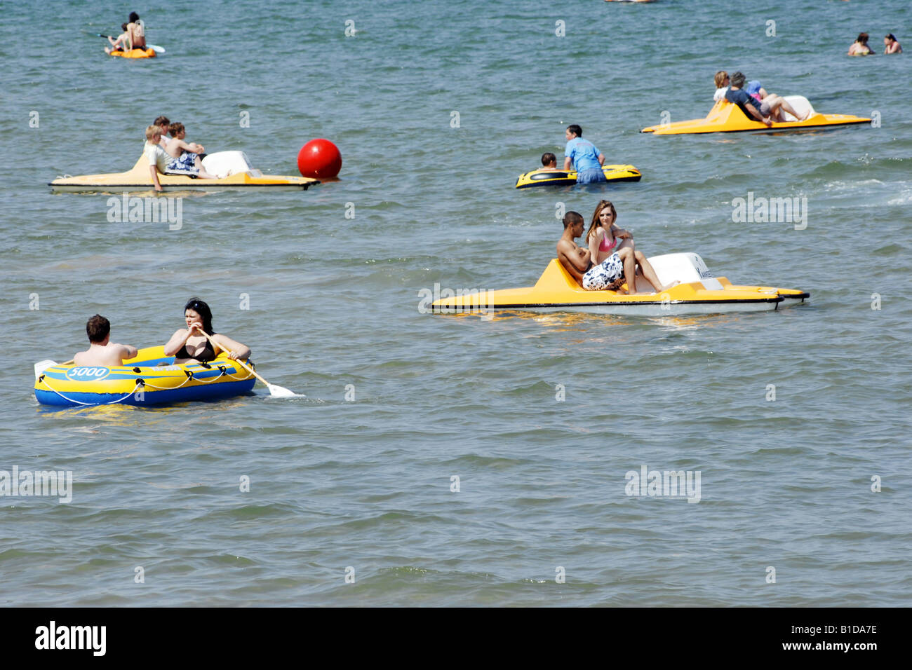 People enjoying the summer sunshine in peddleboats and rubber rafts ...