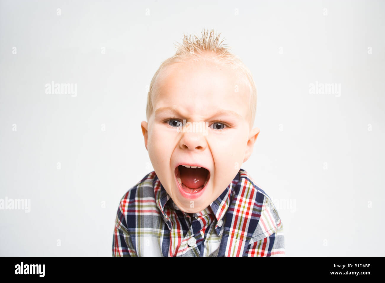Small white blonde boy with spikey hair screaming at you the camera ...