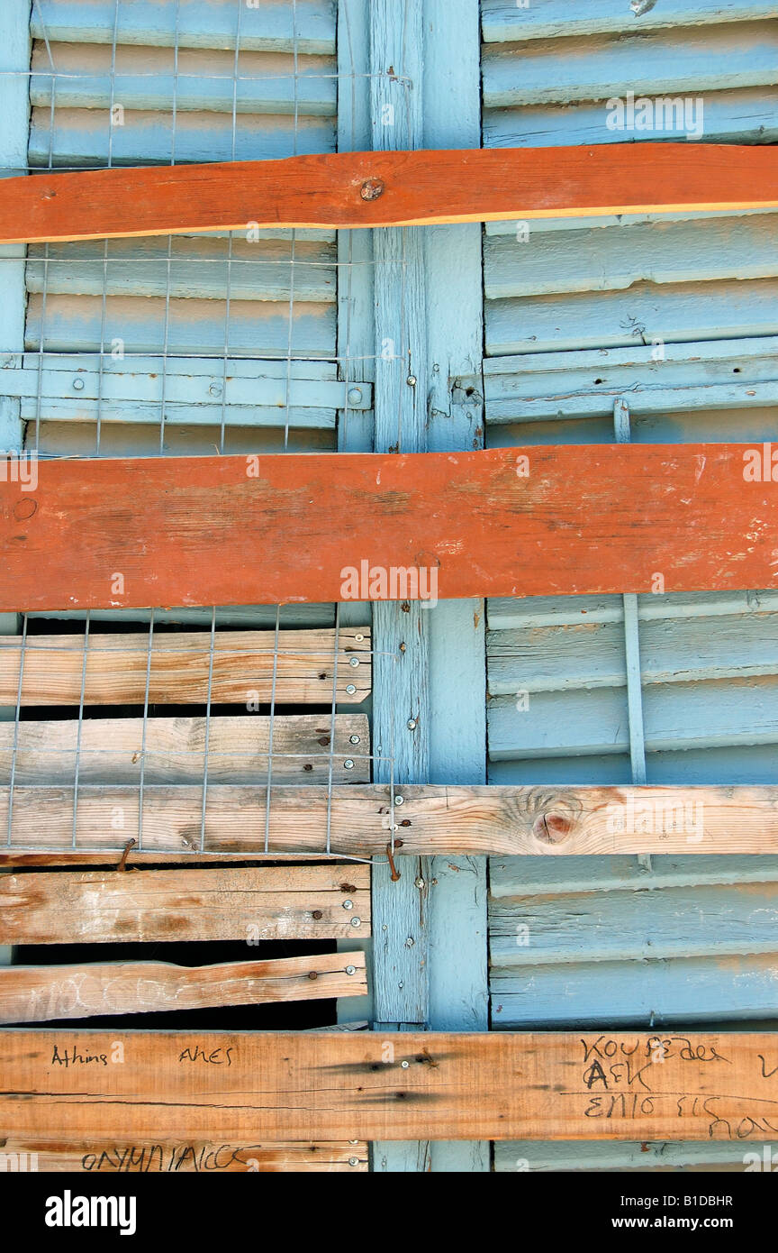 Boarded up weathered window shutter with peeling paint and graffiti ...