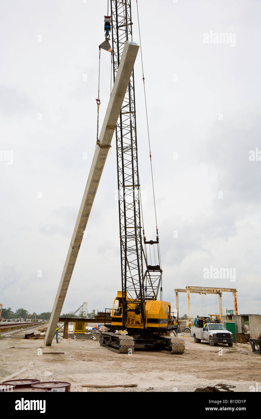 Concrete piling being lifted into place at construction site for ...