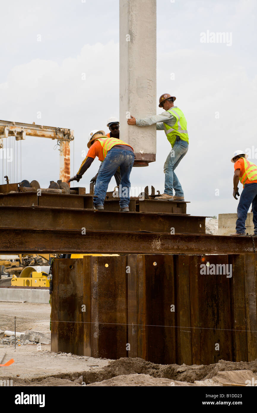 Concrete workers check level of concrete pilings being driven with ...
