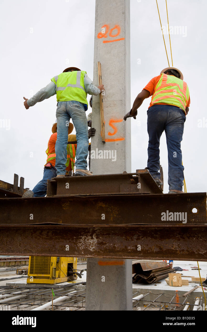 Concrete workers check level of concrete pilings being driven with ...