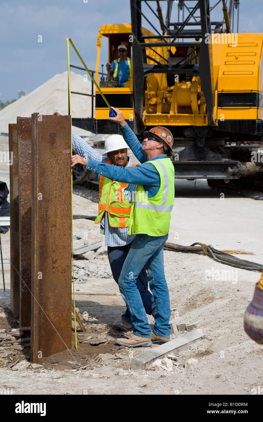 Construction foreman checks alignment of steel sheet piling being ...