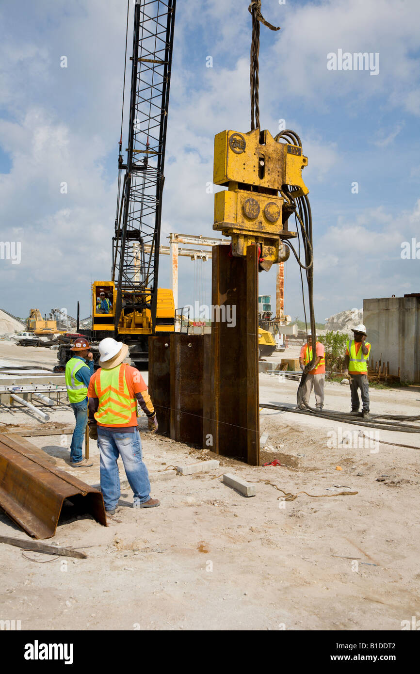 Construction crew uses hydraulic pile driving equipment to drive steel ...