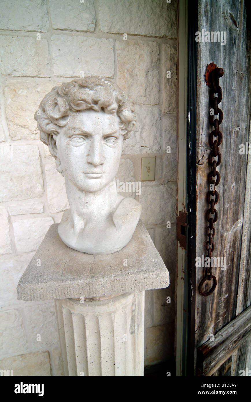 Roman style bust in front of stone wall and next to a wooden door Stock ...