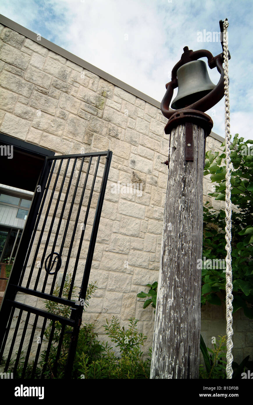 Bell on a pole in front of a stone wall and iron gate Stock Photo - Alamy