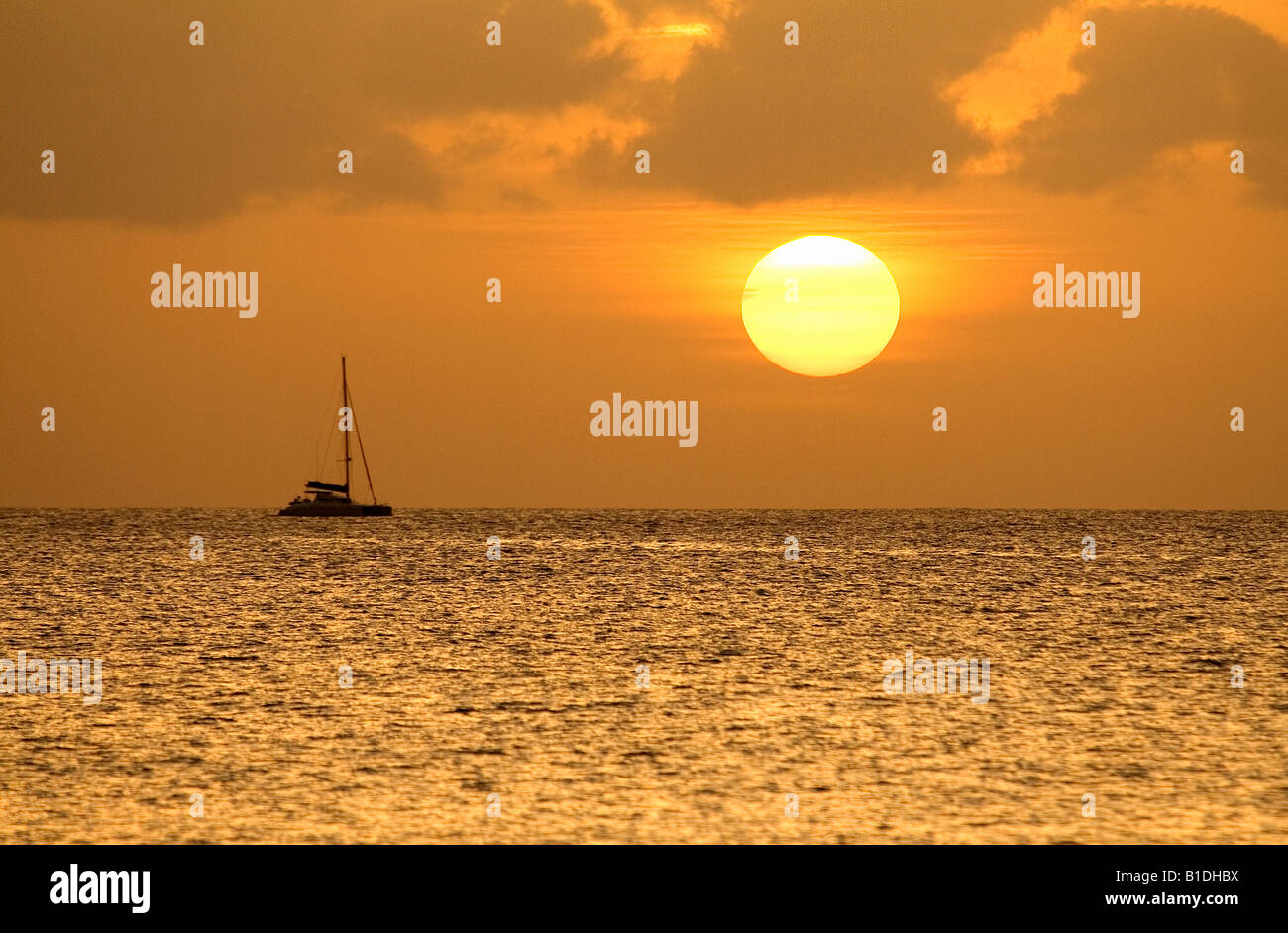 Boat sailing into the sunset on the Caribbean Ocean with the sun like a ...