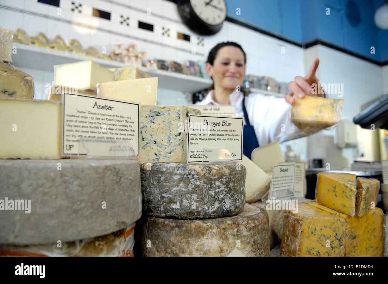 cheesemonger behind counter with cheese in traditional shop Stock Photo ...
