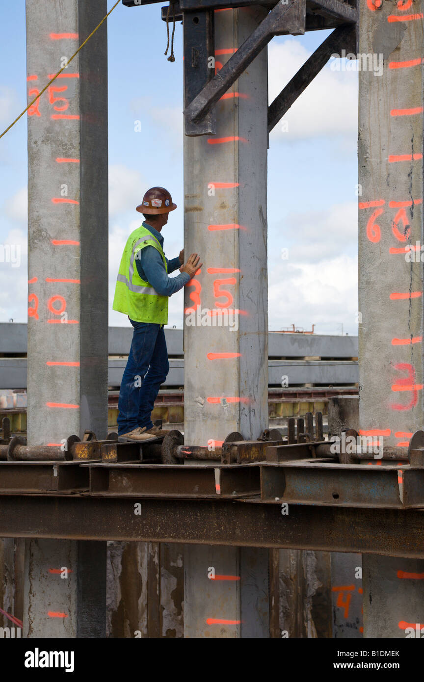 Concrete worker checks level of concrete pilings being driven with ...