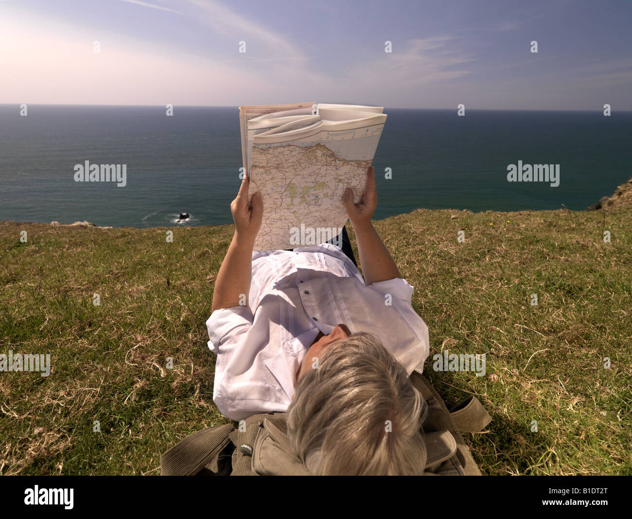 Senior woman walker lying down reading map on headland Stock Photo - Alamy