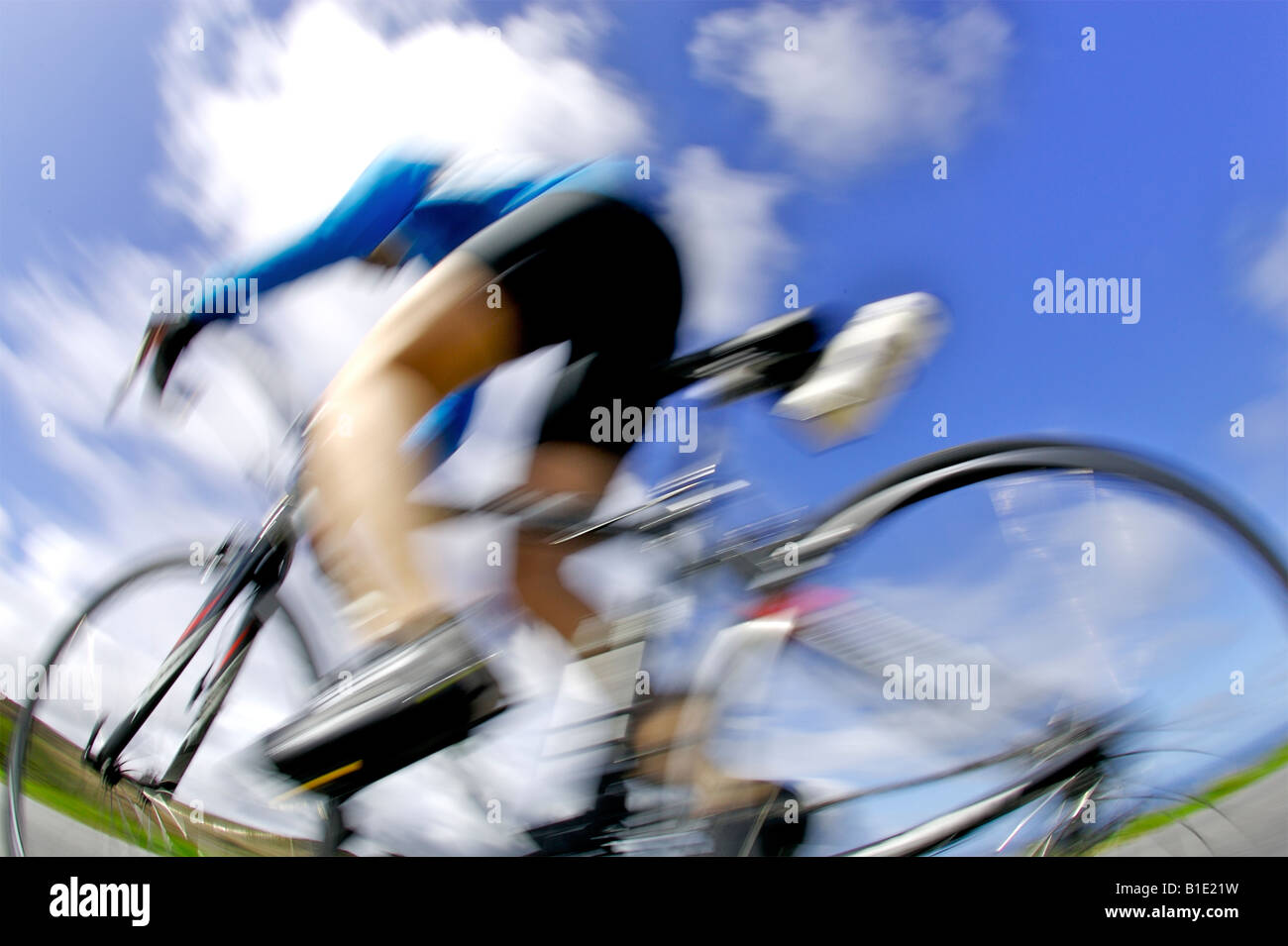 A female cyclist, riding fast along the coast road in Cornwall on a ...