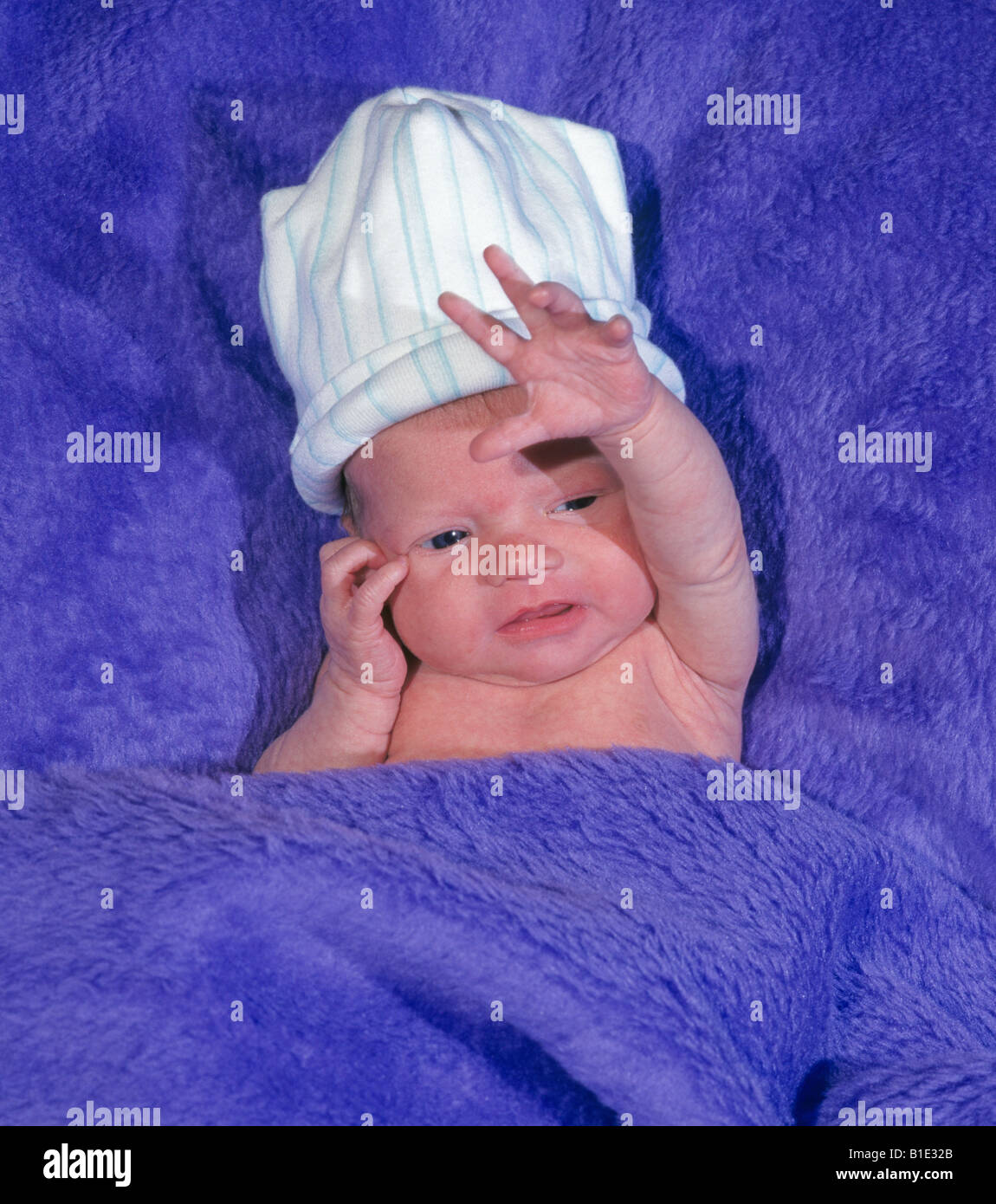 Portrait of a newborn two week old baby girl on her blanket wearing a ...