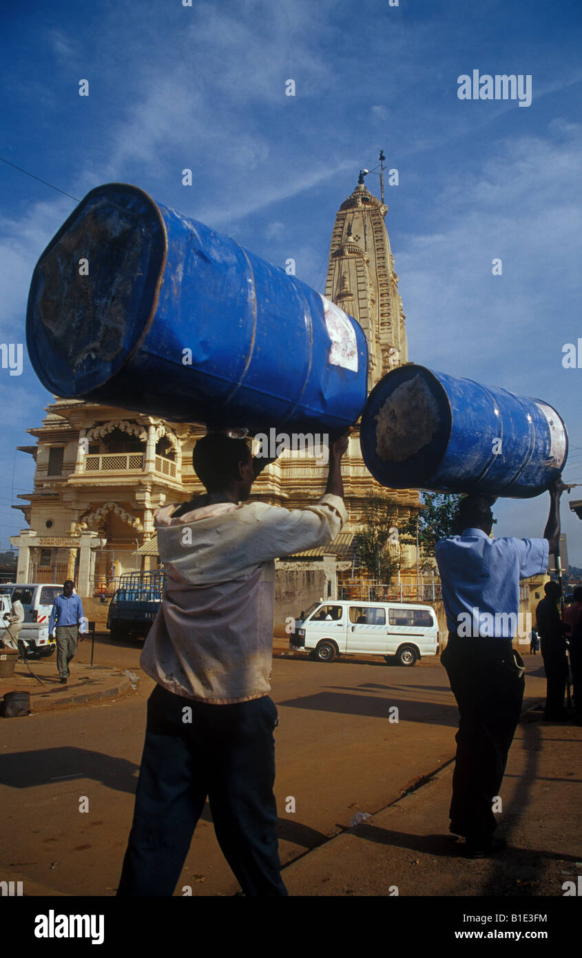 Two men carry oil barrels on their heads in front of a Hindu Temple in ...