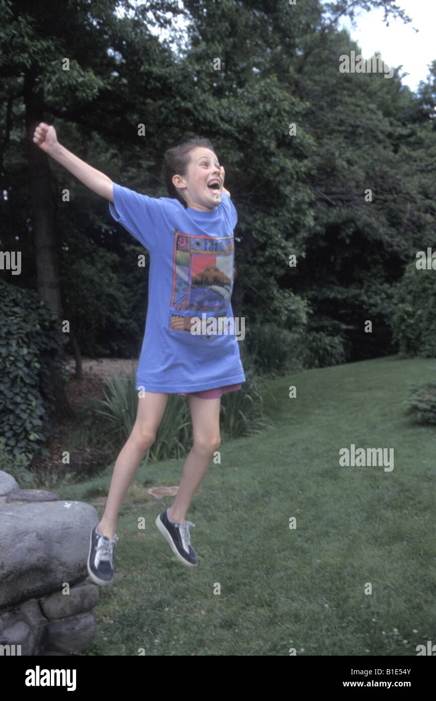 Happy and energetic child takes a leap in a park in Brooklyn New York ...