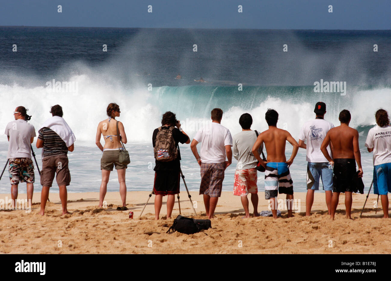 Photographers and spectators line Waimea Beach to view surfers riding ...
