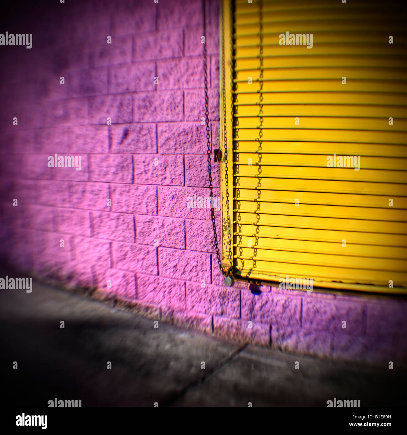 Chain hanging beside Yellow Roller Shutter beside a Purple Wall Stock ...