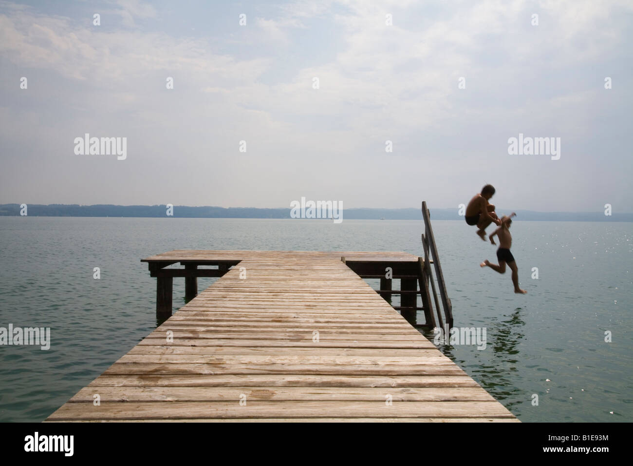 boys jumping into lake from jetty Stock Photo - Alamy