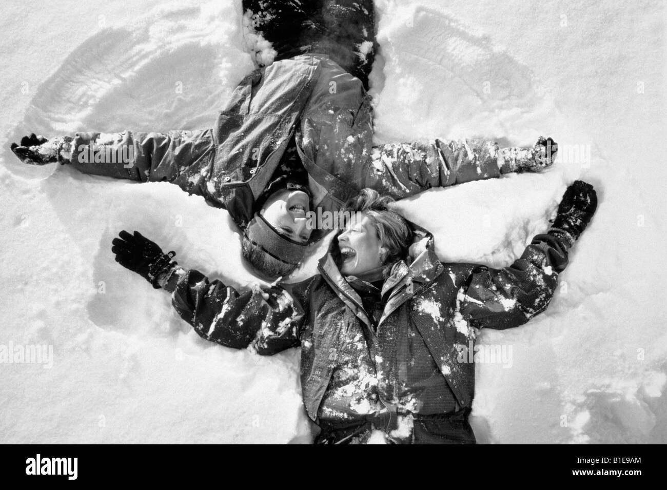 Black & White image of Couple laying in snow making snow angels USA ...
