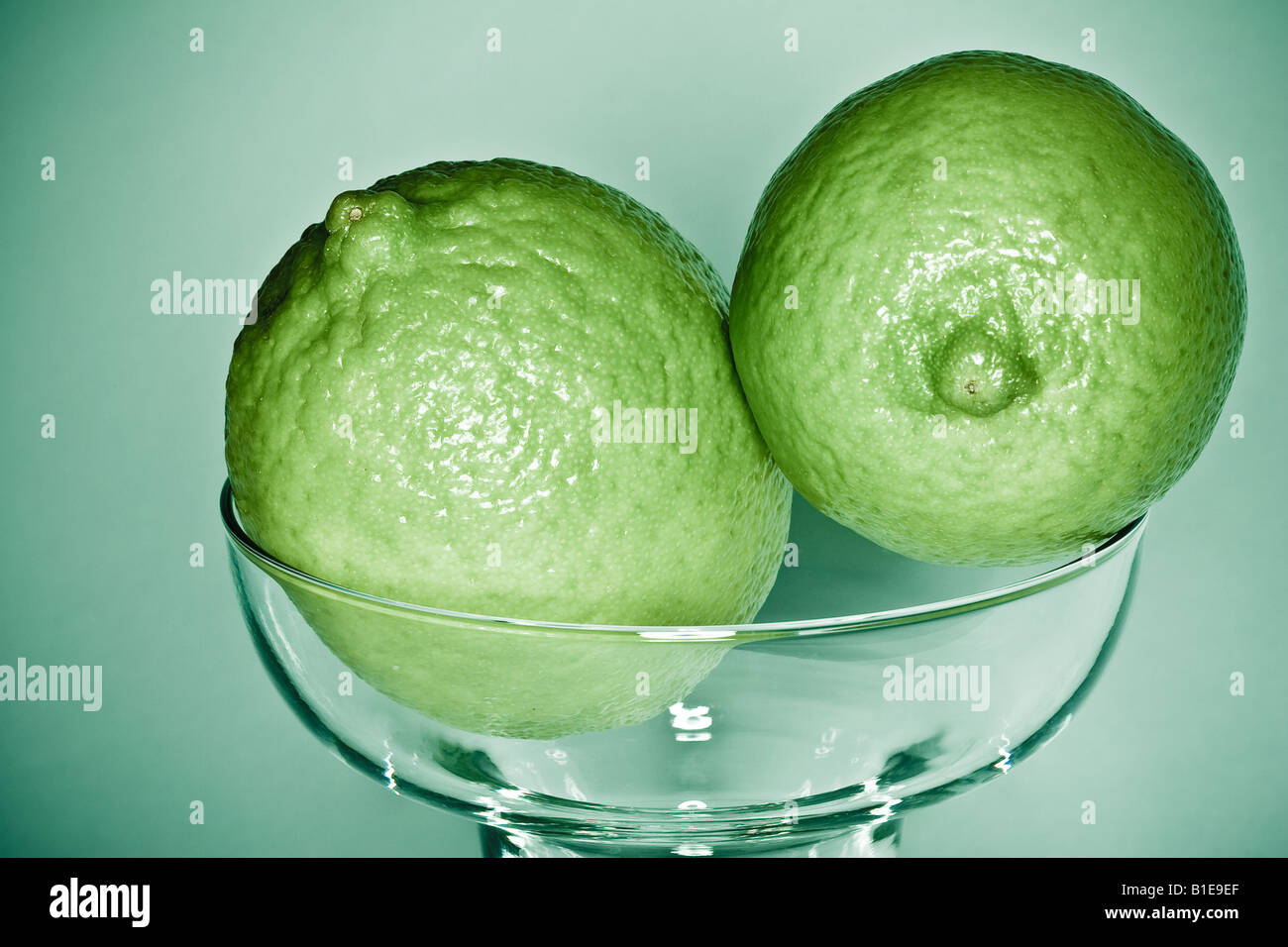 Two limes in a glass isolated against a light green background Stock ...