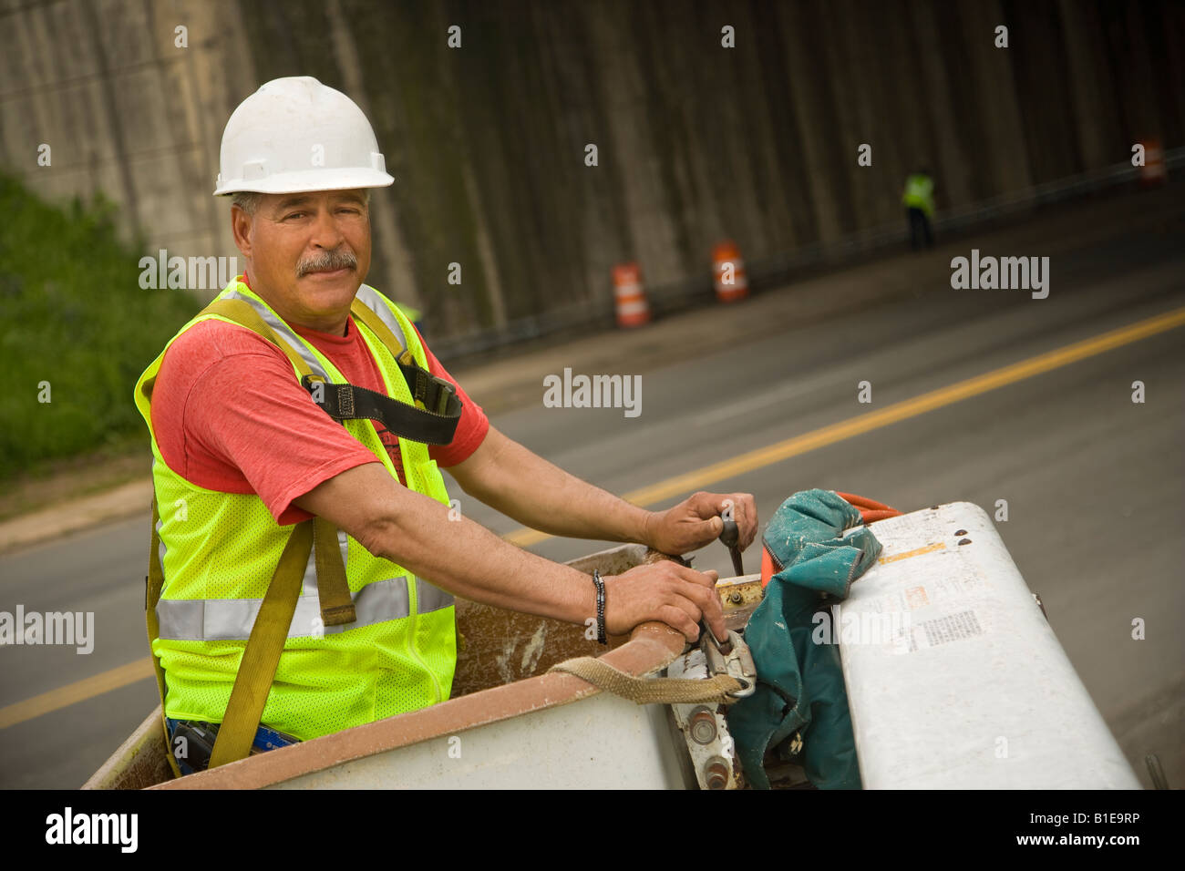 Male Hispanic construction worker operating a lift on the side of the ...