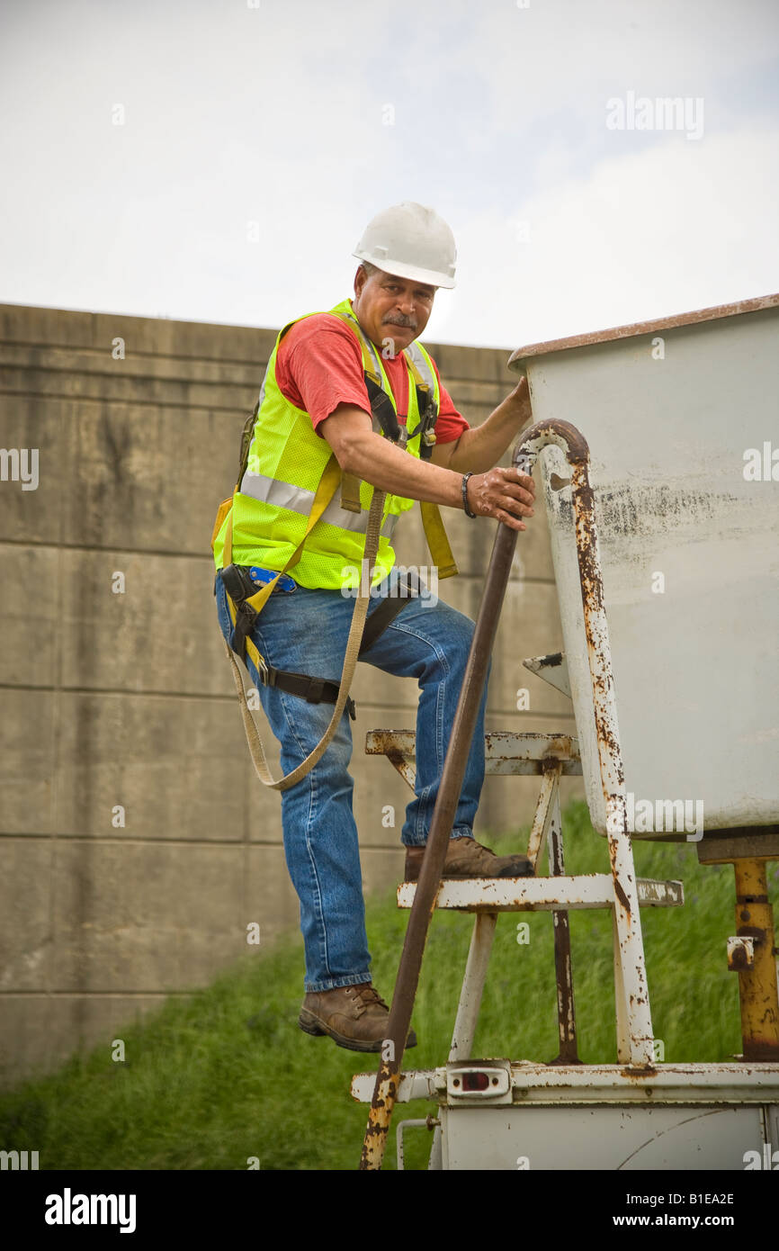 Mature male Hispanic construction worker climbing a ladder into a lift ...