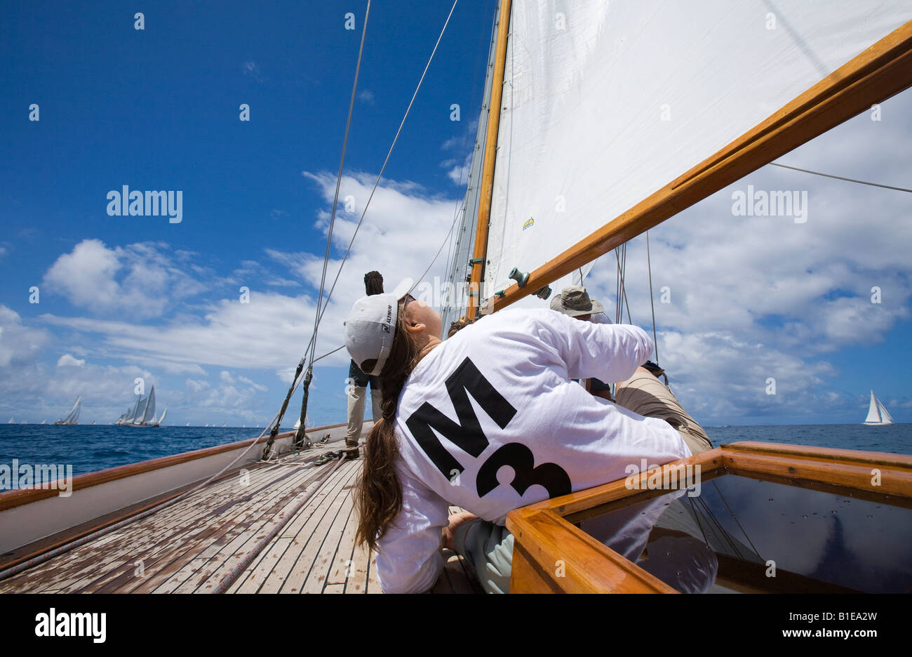 A crew member looks up to check the mainsail on board the sailing yacht ...