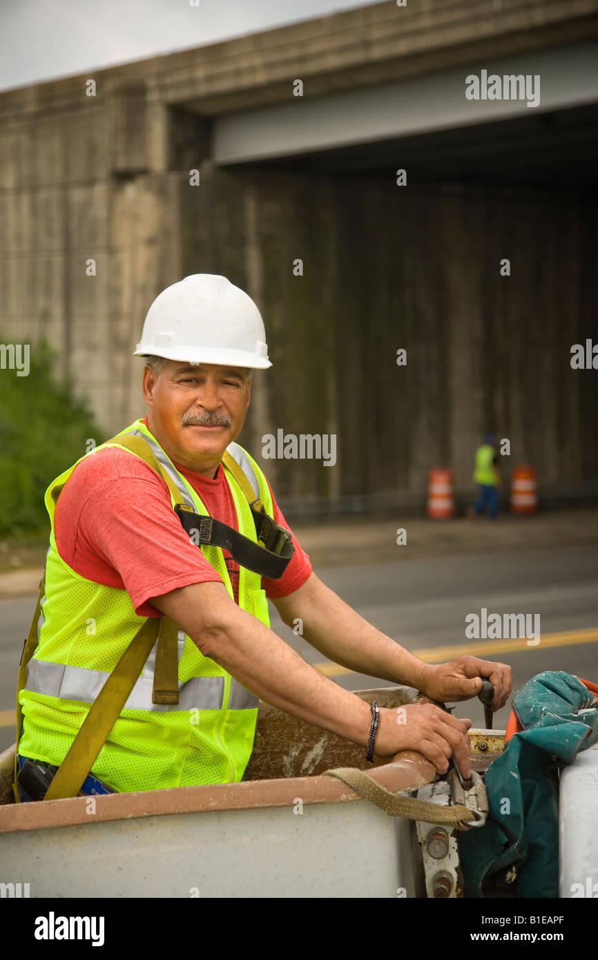 Male Hispanic construction worker operating a lift at a job site ...
