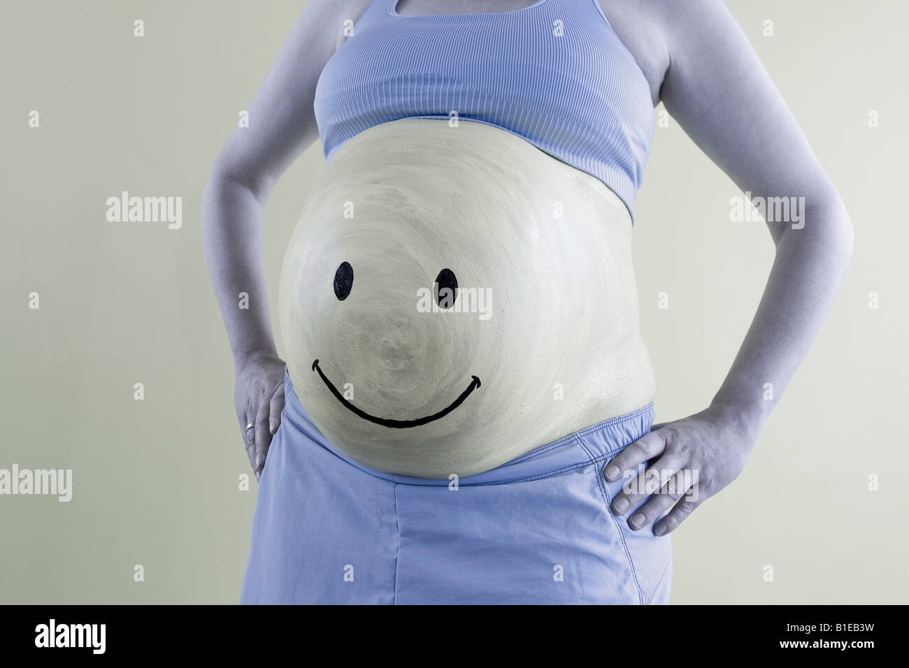 View of pregnant woman's belly with yellow Smiley Face painted on her ...