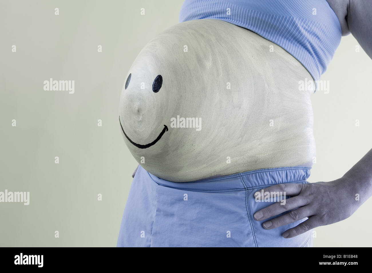 View of pregnant woman's belly with yellow Smiley Face painted on her ...