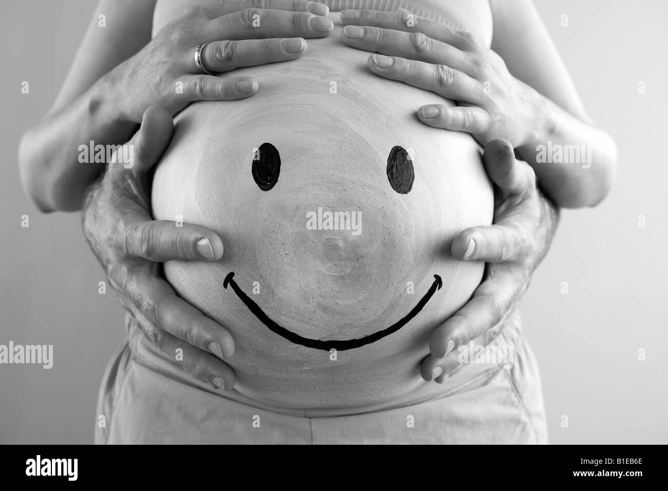 Yellow Smiley Face painted on pregnant woman s stomach and husband ...