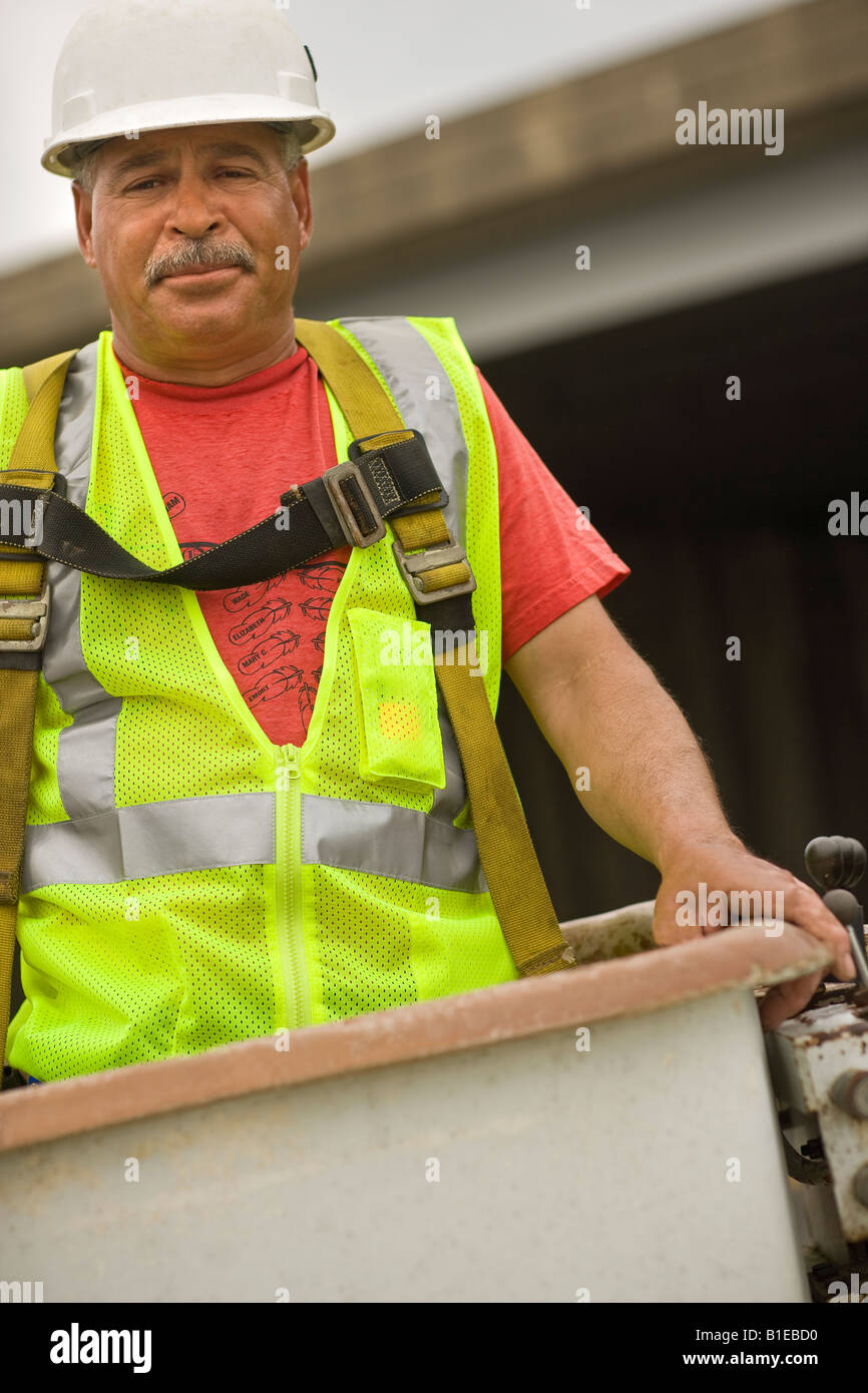 Hispanic construction worker looking at the camera from a lift on a ...