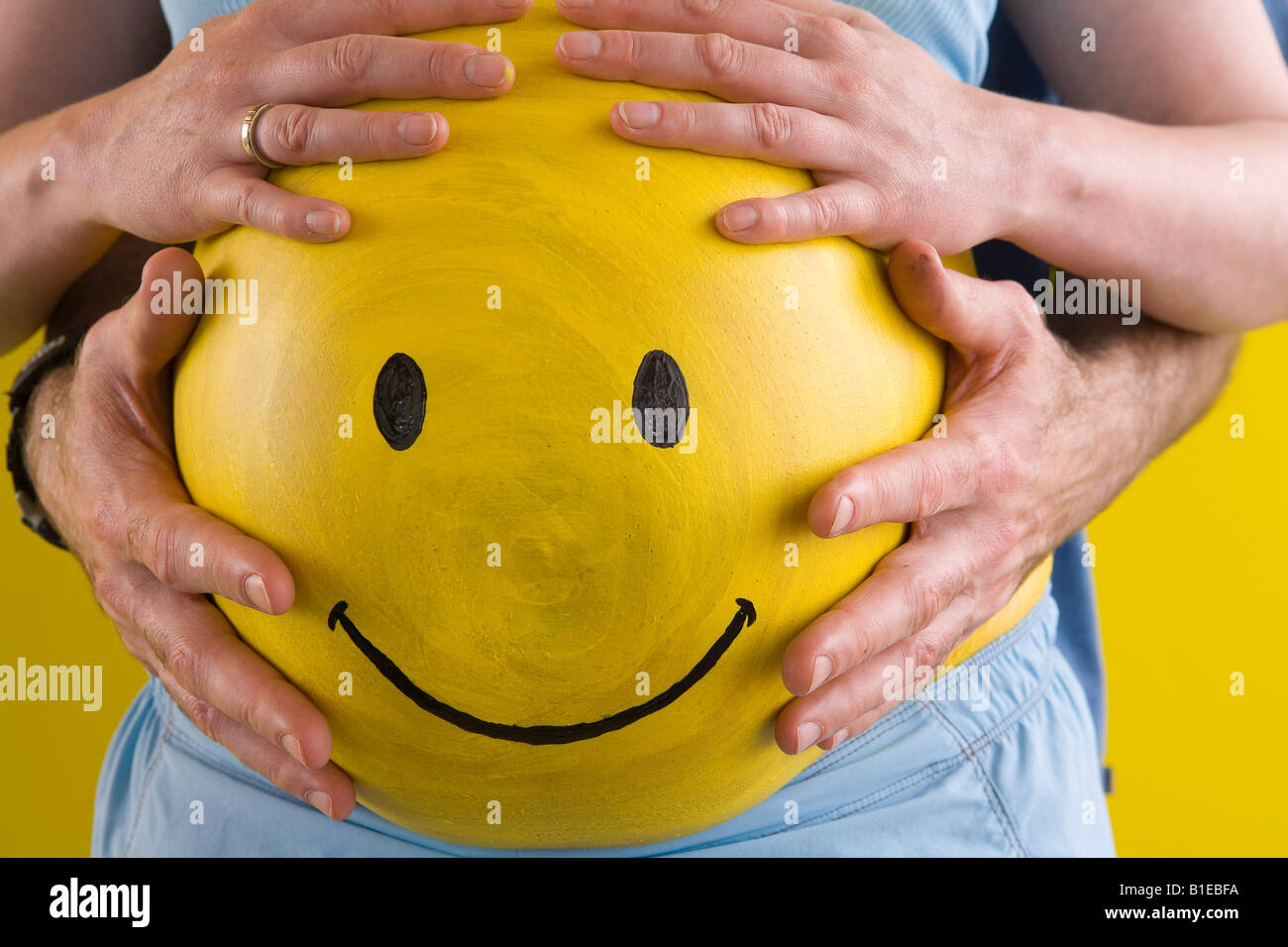 Yellow Smiley Face painted on pregnant woman s stomach and husband ...