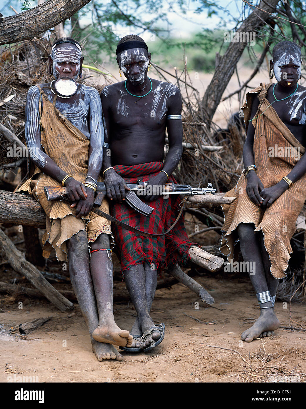 A Mursi man sits with his wife. Once married, Mursi women pierce their ...